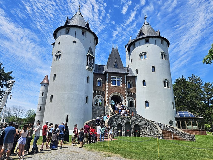 Visitors of all ages line up eagerly to explore Castle Gwynn, their expressions capturing that magical moment when fantasy architecture becomes tangible reality.