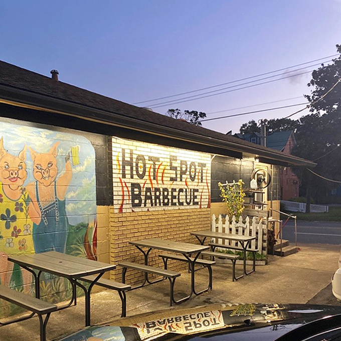 As evening falls, the outdoor seating area becomes an oasis for those who prefer their barbecue with a side of fresh air and charming wall art.