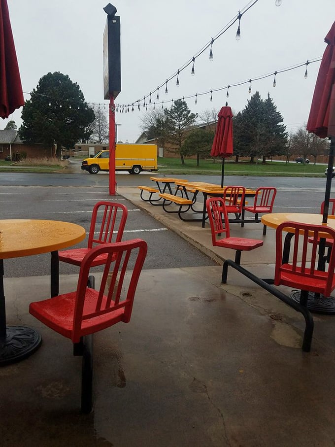 Rain or shine, these cheerful red chairs welcome weary travelers. The string lights stand ready to transform ordinary evenings into something special.