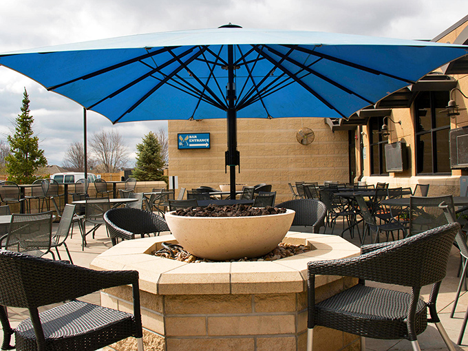 Fire pits and blue umbrellas create an outdoor oasis that makes you forget you're in a restaurant parking lot.