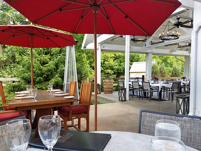 Outdoor dining under red umbrellas offers a peaceful retreat where summer breezes complement every bite and sip of your leisurely meal.