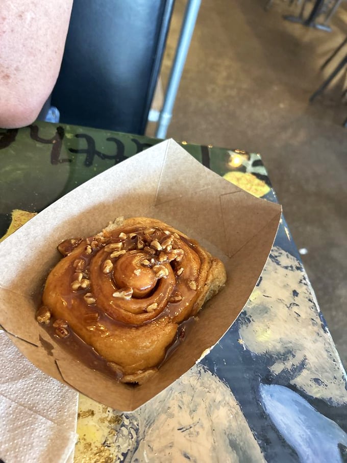 This cinnamon roll isn't just breakfast&mdash;it's an architectural marvel of spiraled dough, with pecans and caramel playing supporting roles in this morning drama.