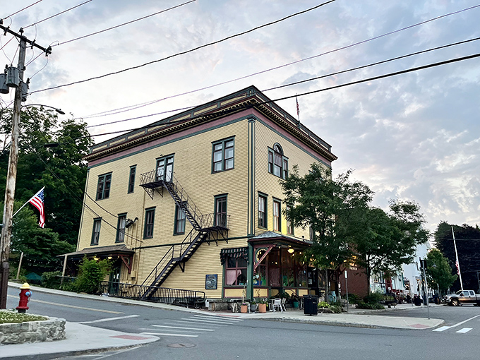 This stately yellow building anchors the corner with old-school dignity, complete with fire escape that doubles as architectural flair.