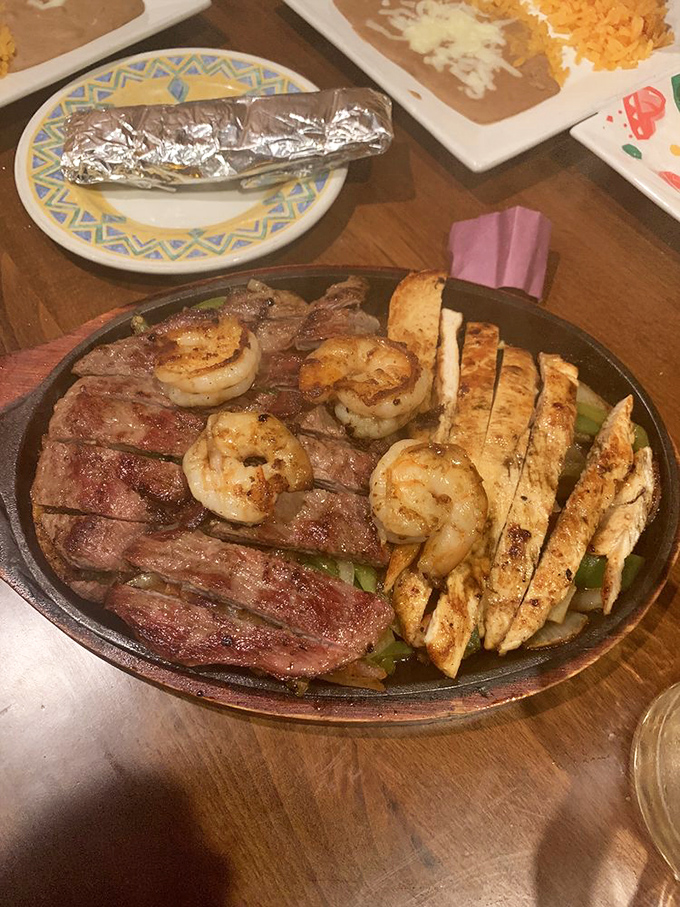 The fajita trinity&mdash;chicken, steak, and shrimp&mdash;arranged on a sizzling platter that announces its arrival before you even see it. Dinner and drama in one package.