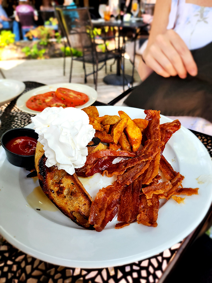 Breakfast reaches its final form with crispy bacon, golden potatoes, and what appears to be a dollop of joy masquerading as whipped cream.