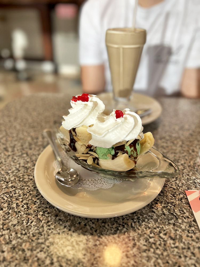 The banana split—that holy trinity of ice cream scoops cradled in nature's perfect dessert vessel, finished with a cloud of whipped cream.