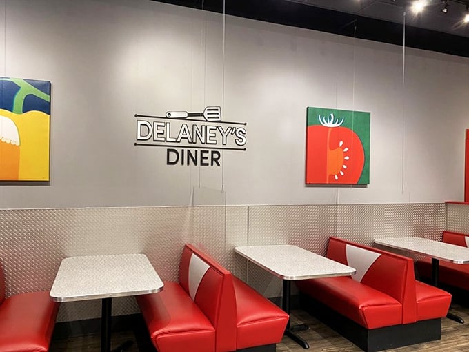 Red booths against white walls with playful food art create that perfect diner atmosphere &ndash; comfortable without being kitschy.