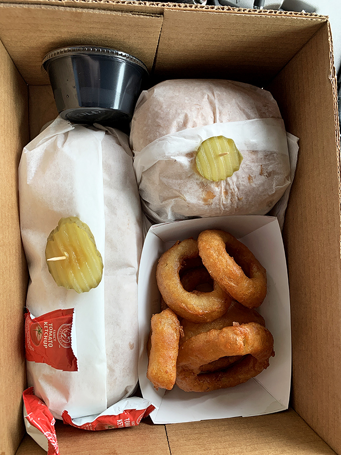 The humble cardboard box becomes treasure chest when filled with Jim's burgers, rings, and the promise of roadside bliss.