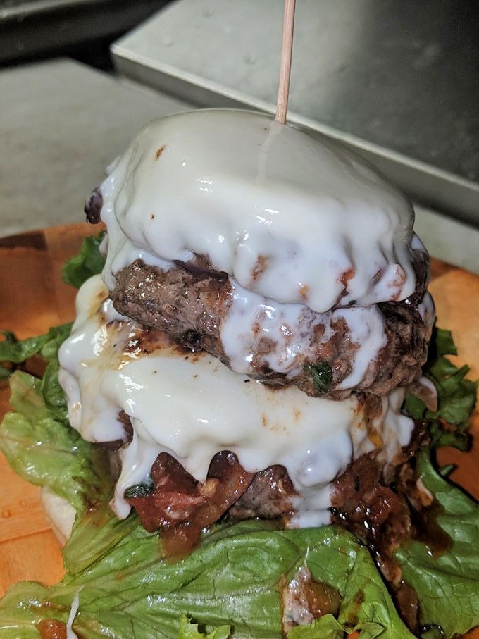 This towering burger creation defies gravity and common sense while delivering maximum satisfaction per bite.
