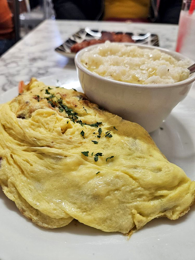 An omelet that looks like it's been practicing its folds for decades, paired with grits so creamy they deserve their own fan club.