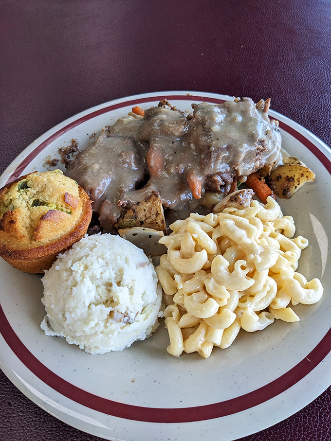 Pot roast that's had a long, meaningful conversation with gravy, alongside mac and cheese and a cornbread muffin that refuses to be upstaged.