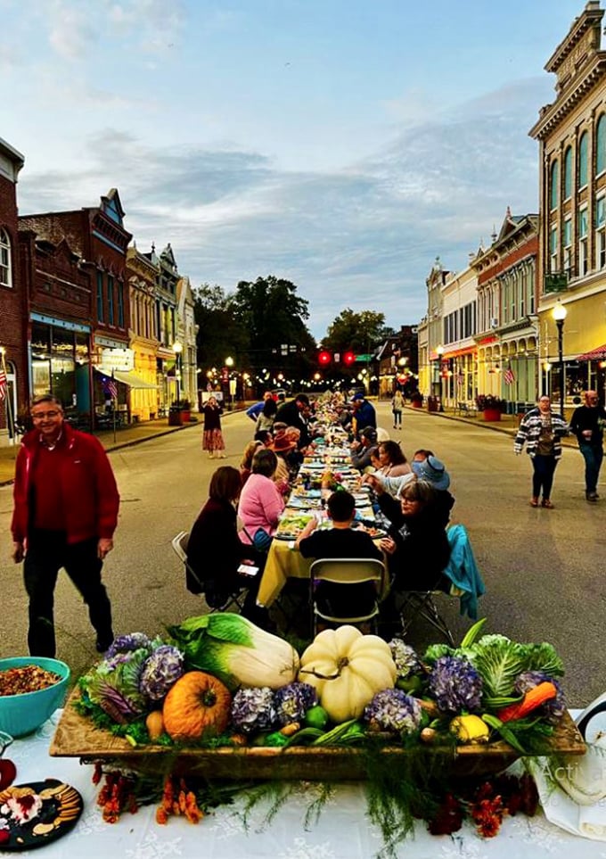 The ultimate community dinner stretches down Main Street at dusk, where neighbors break bread beneath string lights and small-town magic.