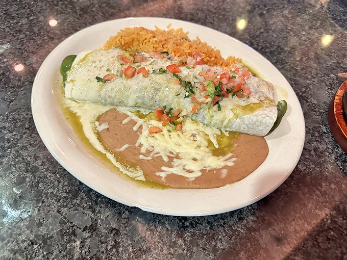 This burrito wears its sauce like a fine garment. The color contrast between green sauce, refried beans, and yellow rice creates an edible Mexican flag.