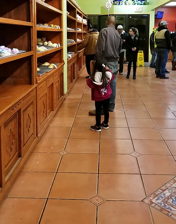 The timeless dance of bakery selection: parents guiding children through the same sweet dilemma they experienced decades ago.