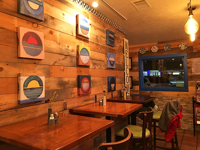 The wooden accent wall adorned with colorful circular art creates the perfect backdrop for conversations that flow as easily as the olive oil.