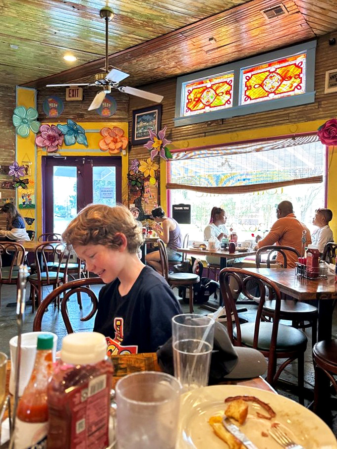 Colorful flower decorations frame a dining room where conversations flow as freely as the coffee, creating that perfect neighborhood buzz.