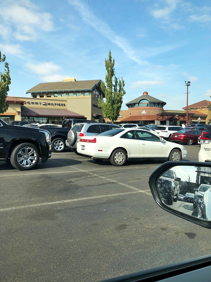 The parking lot battlefield where shoppers circle like hungry sharks, ready to pounce on that one spot opening up near Tommy Hilfiger.