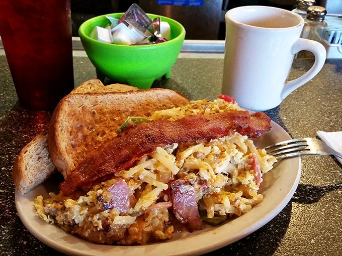 Breakfast alchemy: scrambled eggs, crispy hash browns, and bacon that shatters like glass&mdash;the holy trinity of morning satisfaction on a no-nonsense plate. 