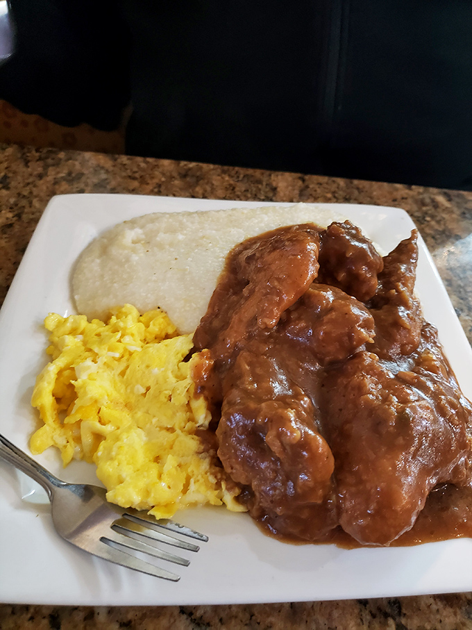 These smothered chicken wings swimming in rich gravy alongside creamy grits and eggs prove that breakfast rules don't apply to soul food champions.