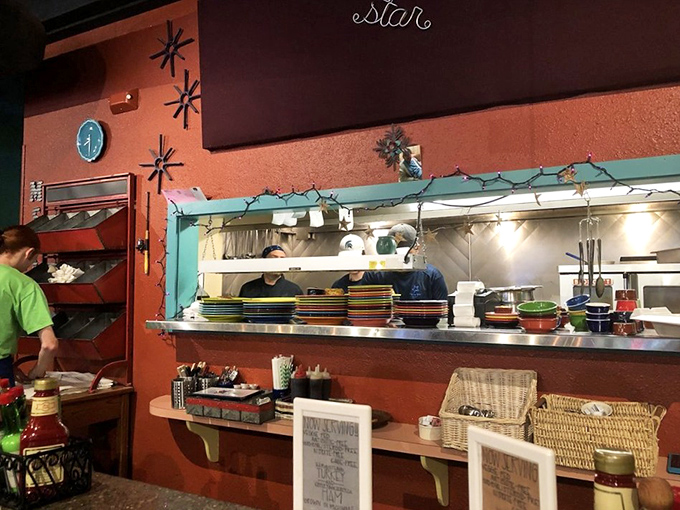 The open kitchen where breakfast dreams materialize. Those colorful plates stacked and ready are about to become someone's perfect morning.
