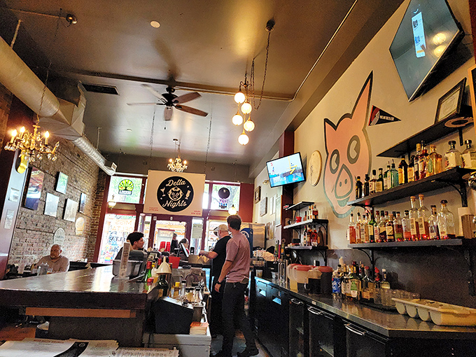 The bar area buzzes with energy as staff craft drinks beneath exposed brick walls and that watchful pig mascot.