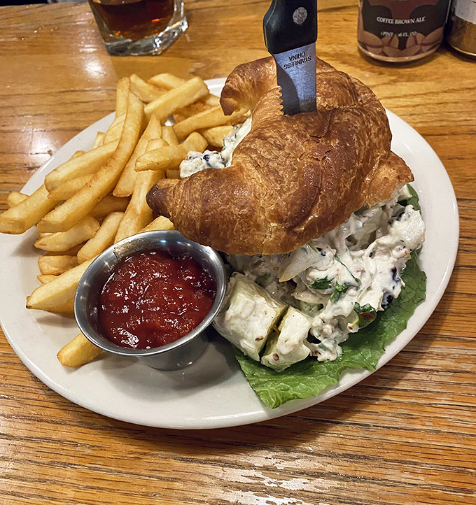 This chicken salad croissant isn't just lunch&mdash;it's edible architecture. Flaky, buttery pastry cradles creamy chicken salad with fries standing at attention alongside.