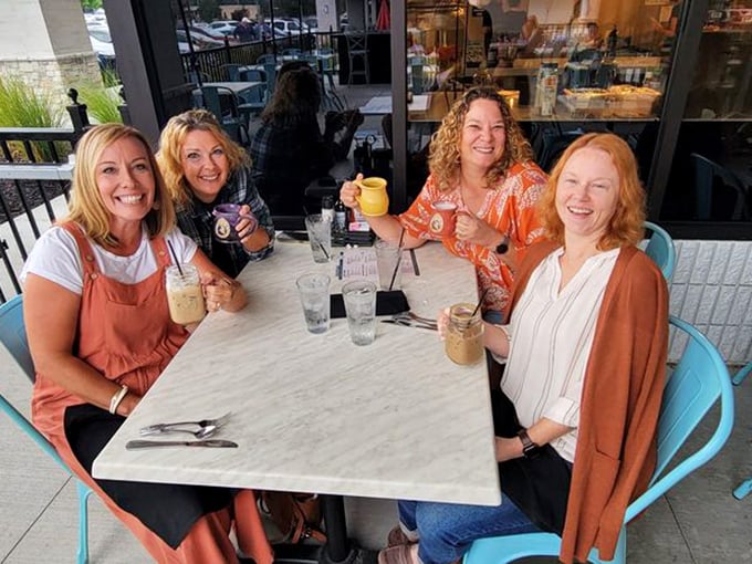 The universal language of brunch friendship: four women raising colorful mugs in a toast to good food and better company.