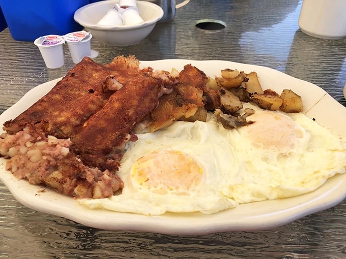 The holy trinity of breakfast perfection: sunny-side up eggs, golden home fries, and crispy scrapple&mdash;a plate that speaks the universal language of satisfaction.