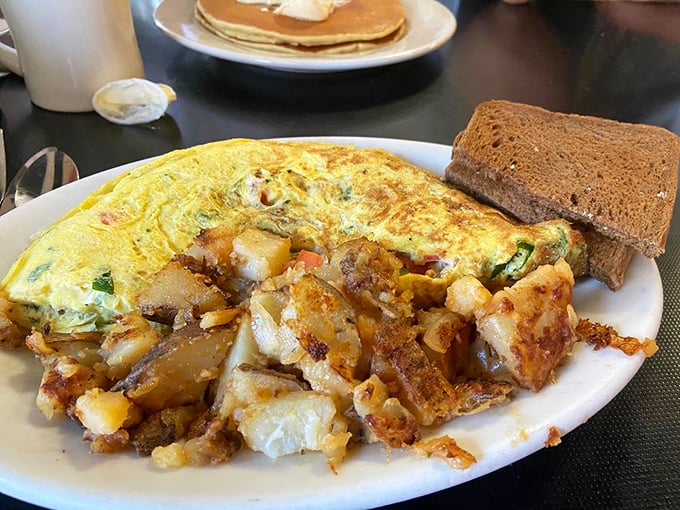 This isn't just an omelet&mdash;it's a golden envelope stuffed with treasures, escorted by home fries that have achieved crispy-tender perfection.