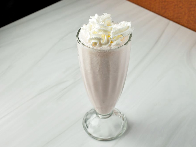 A classic strawberry milkshake that looks like it time-traveled from 1955, complete with whipped cream crown and nostalgic glass.