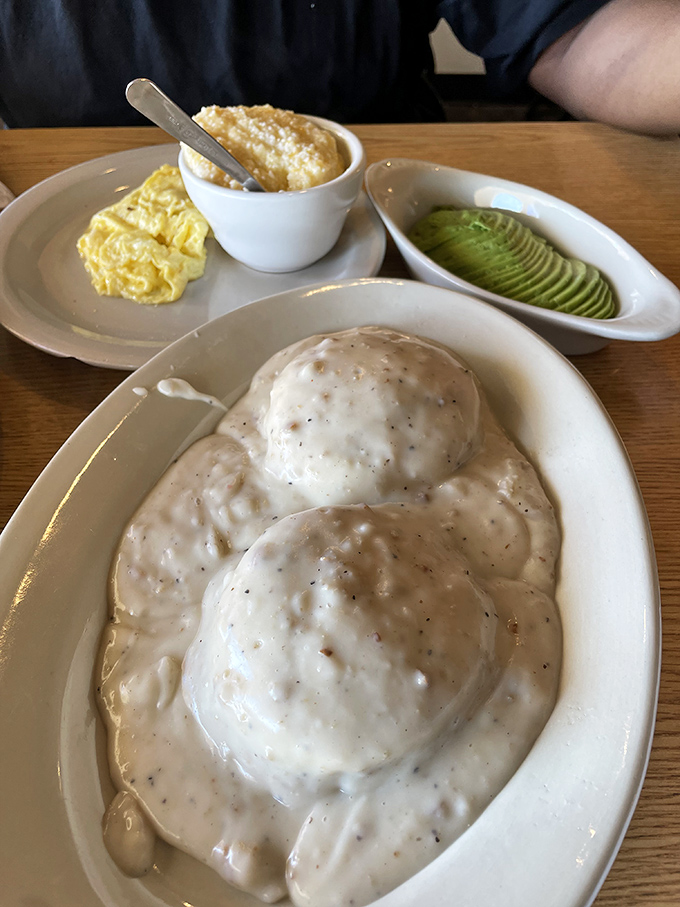 Biscuits swimming in gravy with perfectly sliced avocado on the side – Southern comfort meets California cool on one magnificent plate.