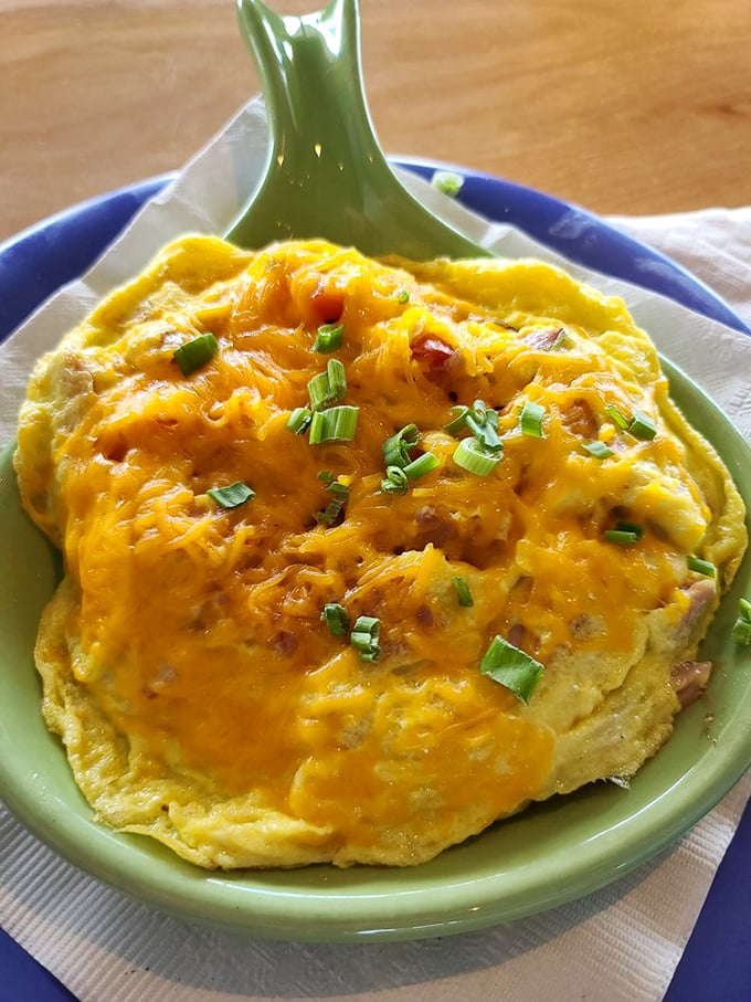 An omelet that's been to cheese finishing school. This golden creation, topped with melted cheddar and scallions, is breakfast comfort in its highest form.