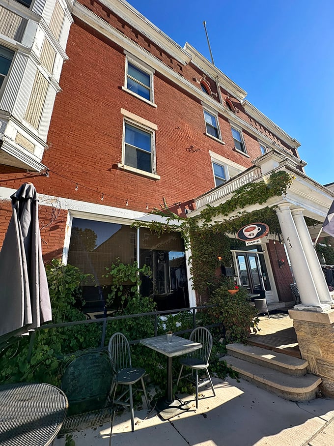 This café's vine-covered entrance creates the perfect transition from historic street to caffeinated sanctuary. The outdoor seating looks like it belongs in a European sidewalk scene.