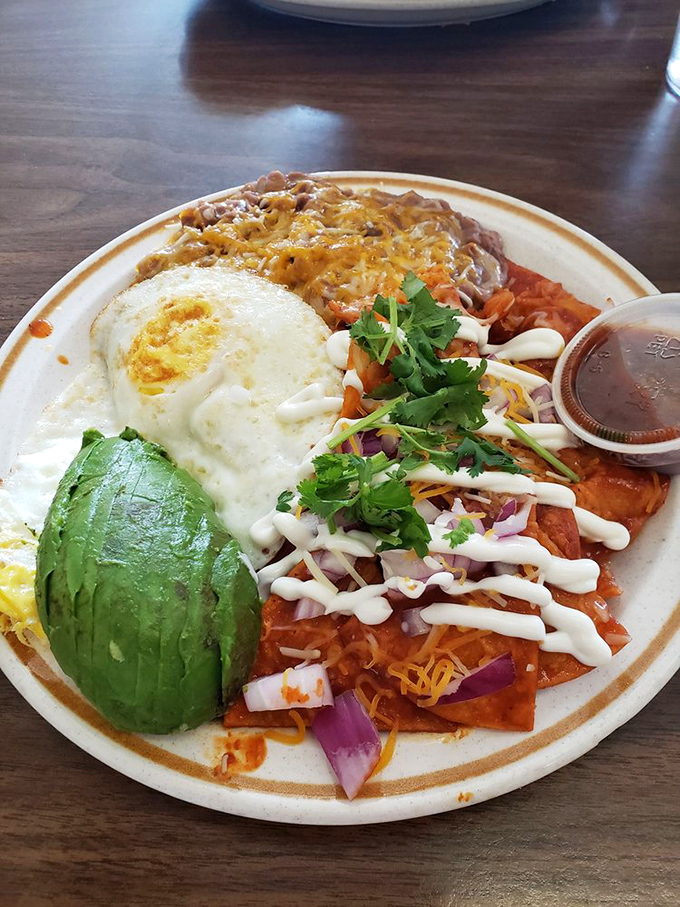Chilaquiles that dance between traditions—crispy, saucy, creamy, and fresh. That half avocado is the emerald crown jewel of breakfast royalty.