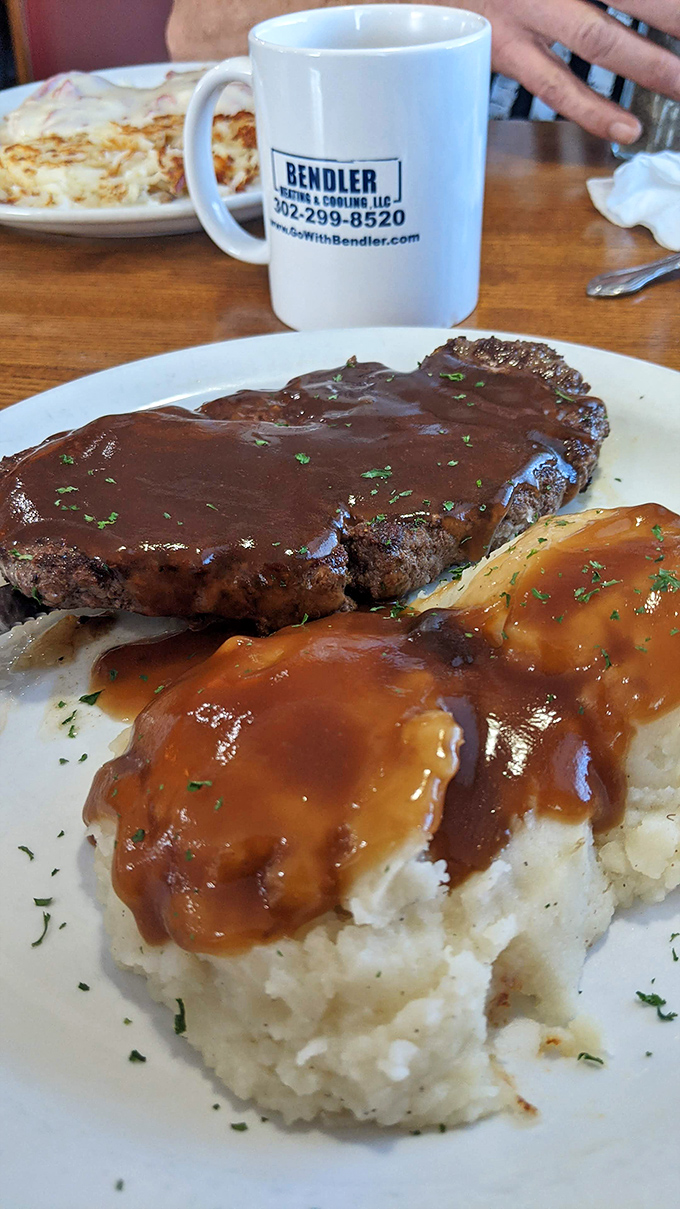 Chopped steak smothered in gravy alongside cloud-like mashed potatoes. This is what comfort food looked like before Instagram made everything precious.