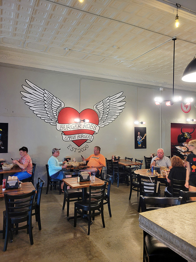 Under the watchful eye of the winged BurgerRobs logo, diners engage in the sacred ritual of burger appreciation.