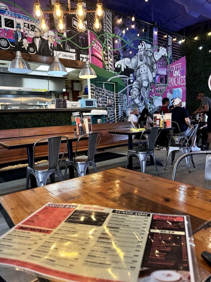 Diners enjoying their meals beneath pop culture murals&mdash;because nothing complements eggs Benedict like a side of nostalgic wall art.