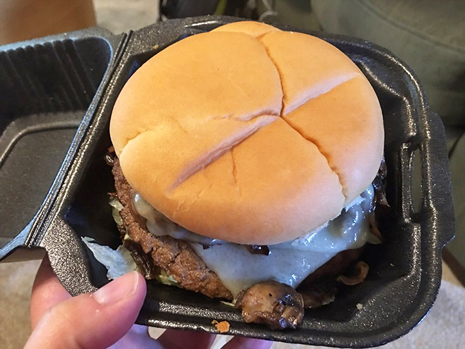 A burger so thick it deserves its own zip code, hiding beneath a humble bun like Clark Kent concealing superpowers.