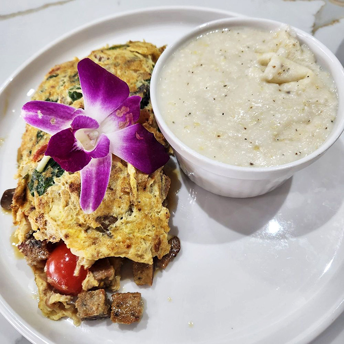 This omelet wearing an orchid like it's heading to the breakfast prom, accompanied by grits that deserve their own fan club.