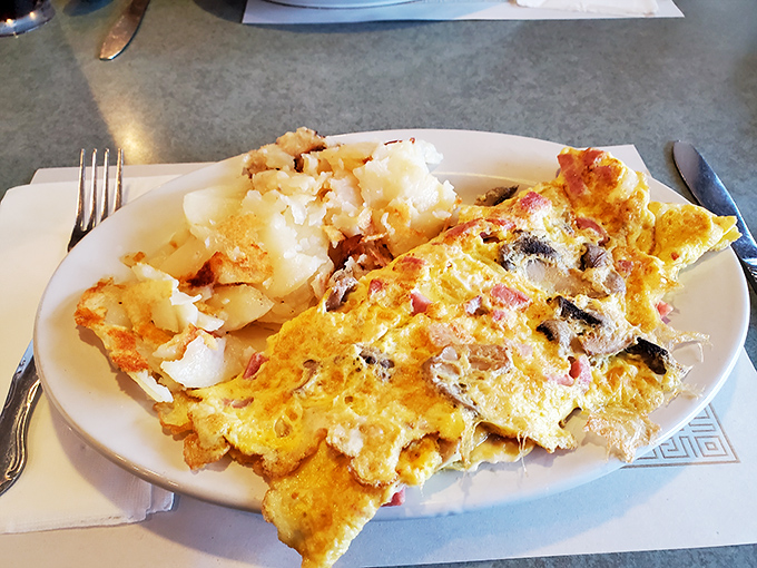 An omelet that's seen things – packed with fillings and paired with home fries that have achieved that mythical balance of crispy exterior and fluffy interior.