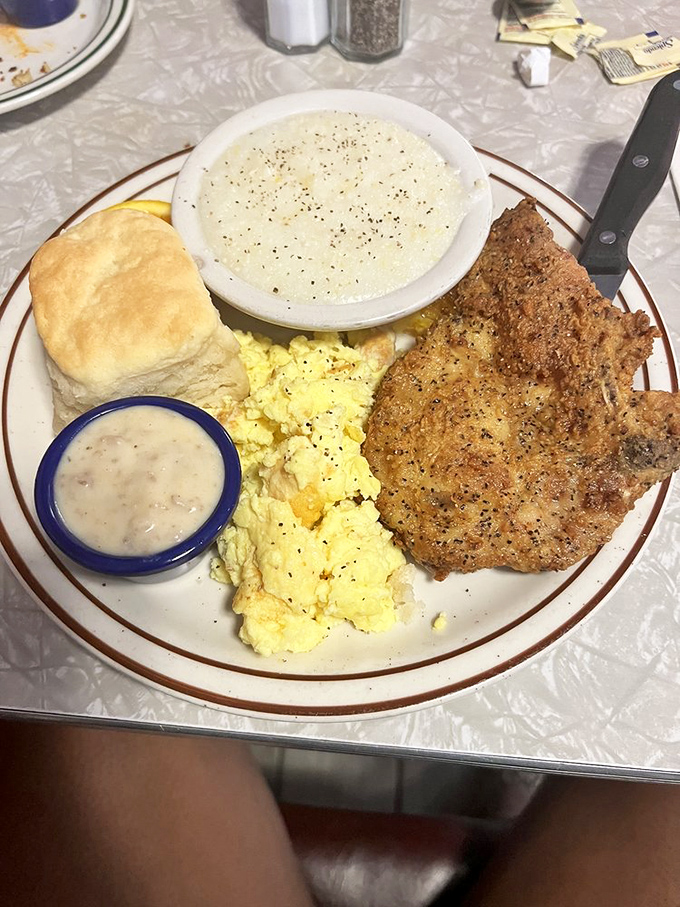 A triumvirate of breakfast perfection: crispy pork, cloud-like eggs, and a biscuit standing by to soak up every last drop.