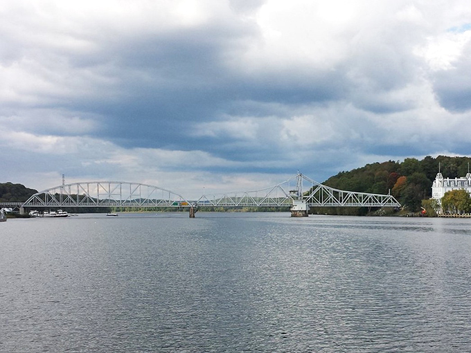 The Connecticut River flows beneath this engineering marvel, connecting Essex to neighboring towns while boats glide beneath like threading a needle.