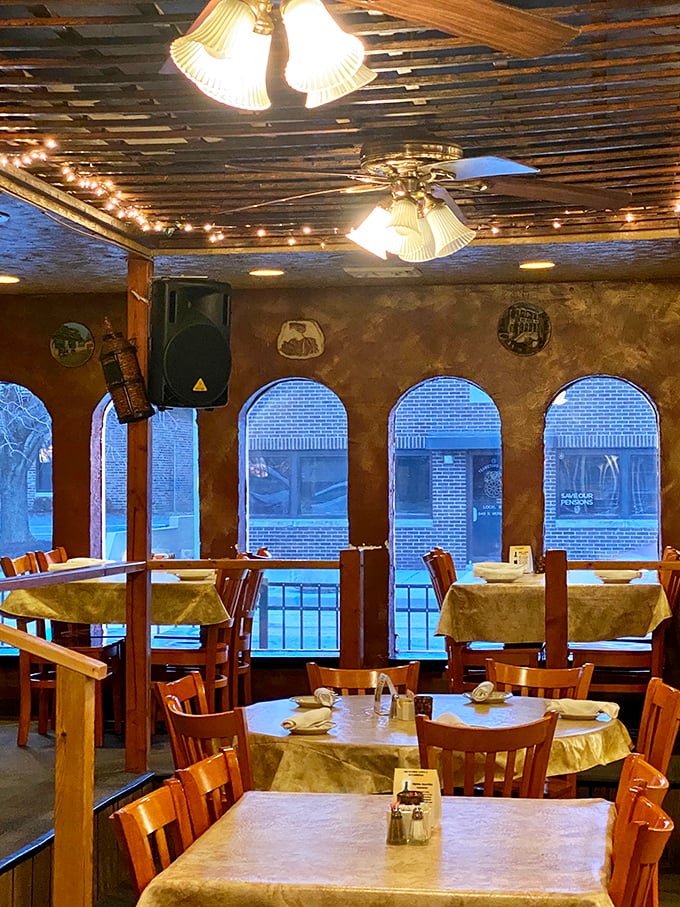 Arched windows frame the dining experience like a living postcard from Athens. String lights add that touch of everyday magic.