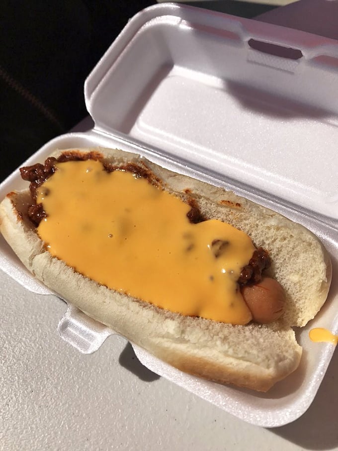 A chili dog that means business, nestled in its takeout container. That melted cheese creates the perfect golden blanket for this handheld masterpiece.