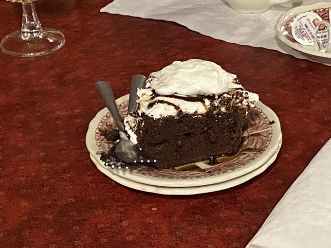 A slice of chocolate cake substantial enough to qualify as real estate, topped with a cloud of whipped cream for good measure.
