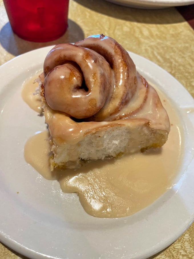 This cinnamon roll isn't just dessert—it's a spiral-shaped miracle swimming in sweet glaze that makes resistance completely futile.