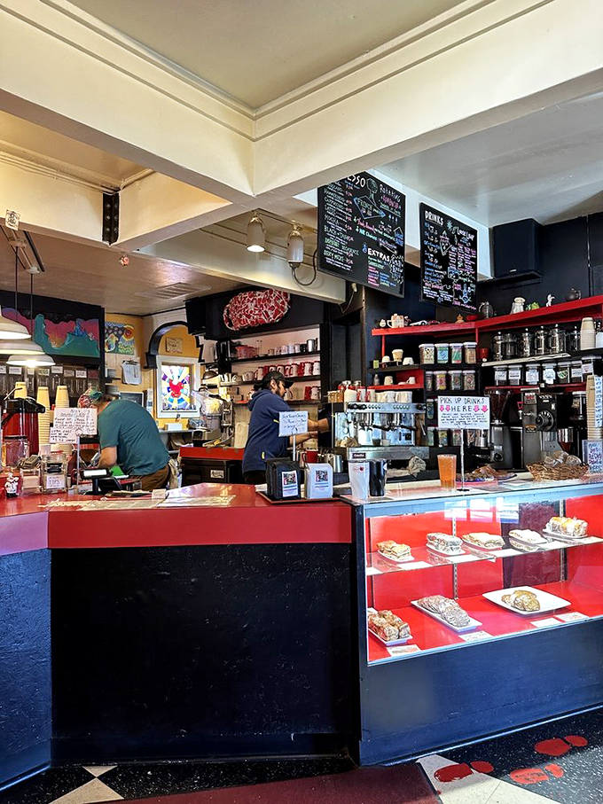 The counter where magic happens&mdash;red, black, and stocked with pastries that make waiting for your order feel like Christmas morning.
