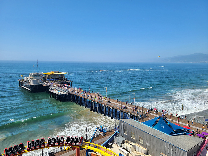 A wooden pathway stretching into the Pacific, where fishing poles and ice cream cones coexist in perfect harmony under the California sun.
