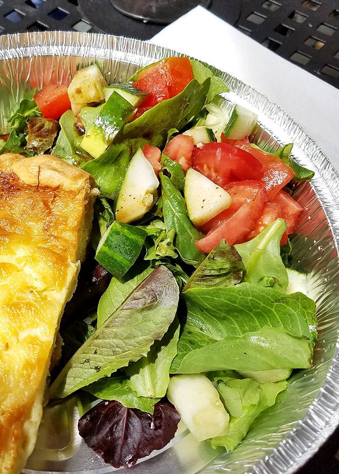 A slice of quiche with a fresh garden salad. When you need to pretend you're being healthy before ordering that second slice of pie.