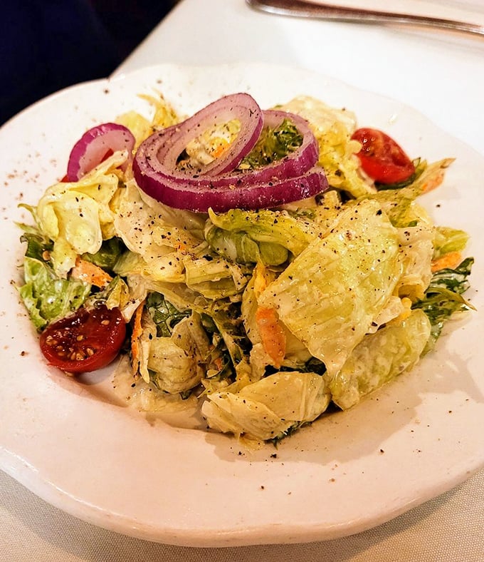 A house salad that doesn't just phone it in&mdash;crisp lettuce, vibrant tomatoes, and red onions that actually contribute to the conversation.